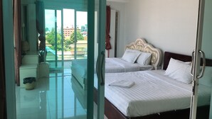 Quarto de hotel com duas camas, varanda e vista para edifícios, e porta de vidro que dá para uma área de varanda.