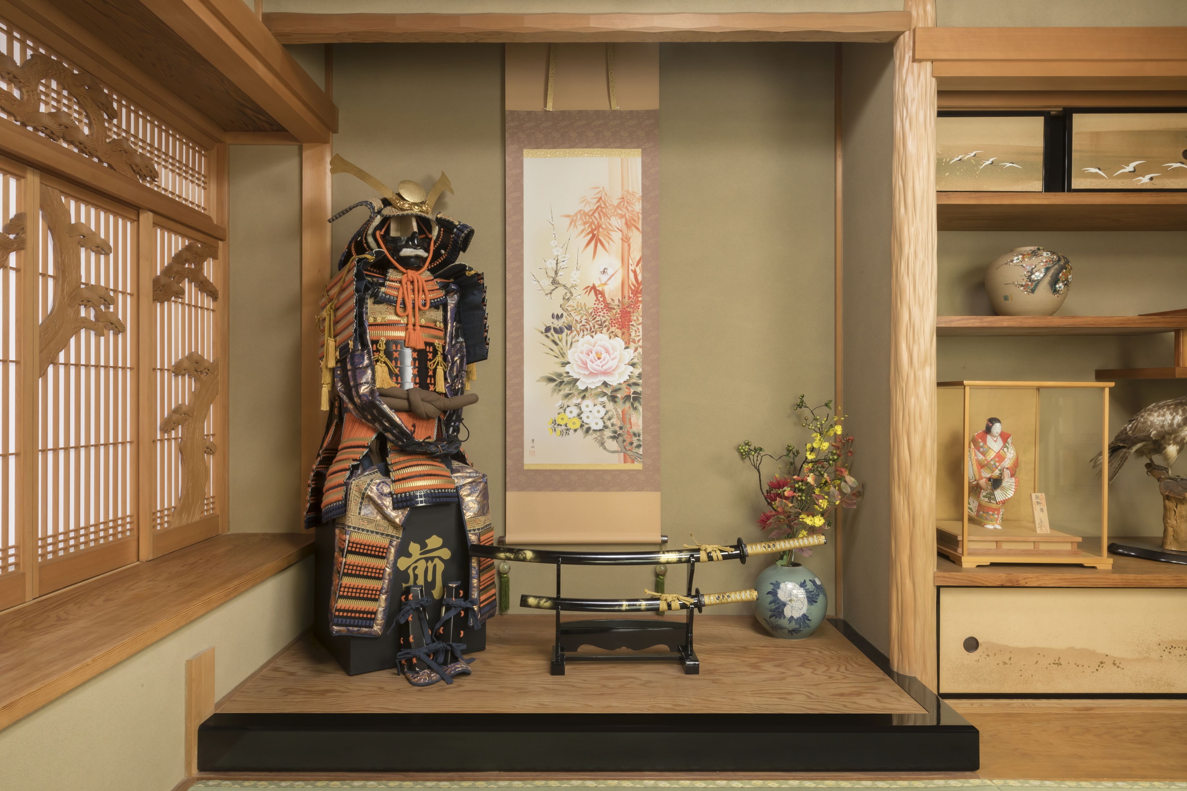 Um quarto japonês tradicional com tatames, um painel shoji, um pergaminho pendurado e uma exibição de quimonos e uma espada samurai.