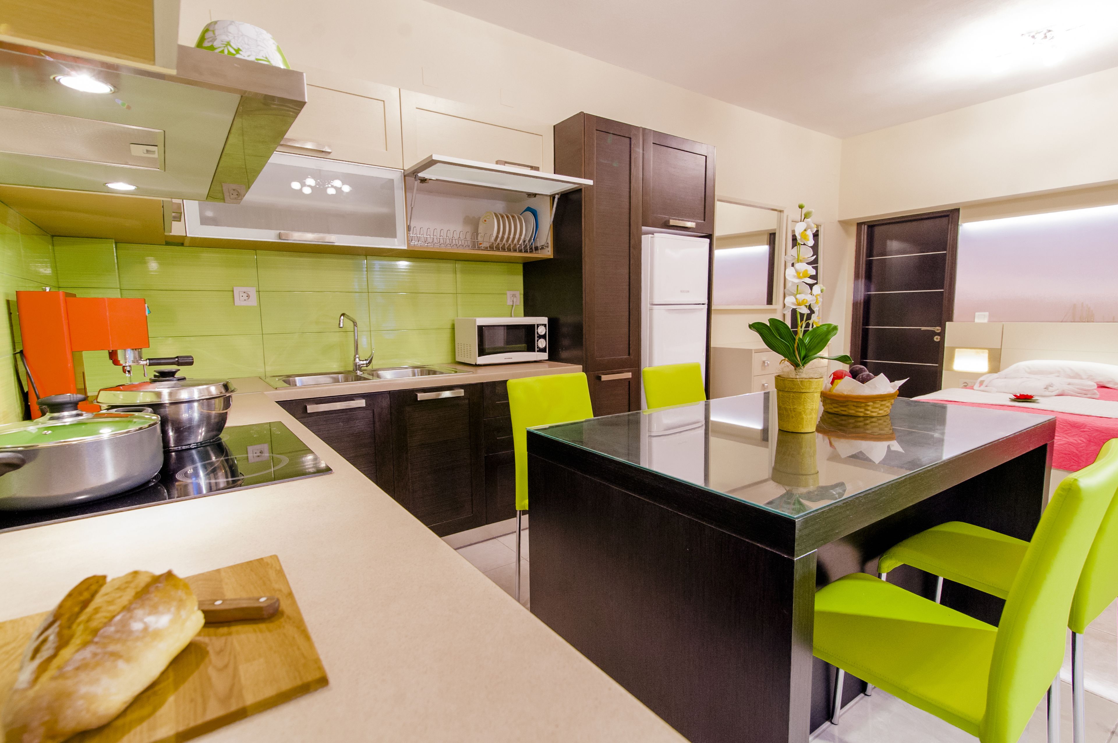 Uma cozinha moderna com uma ilha central, cadeiras verde-claras e uma geladeira.