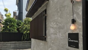Um edifício com uma placa que diz "NOWTRAVEL ShinOsaka" e uma lâmpada pendurada.
