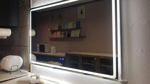 Casa de banho com um espelho grande, dispensador de toalhas e uma estante com livros.