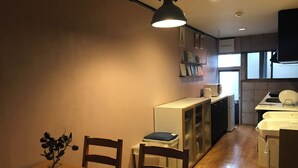 Uma cozinha compacta com área de refeições, piso de madeira e luminária pendente.