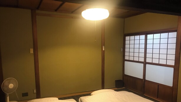Quarto com duas camas, um ventilador e um tradicional ecrã shoji.
