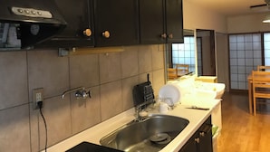 Uma cozinha moderna com armários escuros, uma pia de aço inoxidável e piso de madeira.