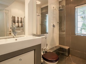 Uma casa de banho moderna com chuveiro, sanita e lavatório.