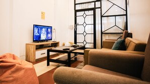 Uma sala de estar com televisão, sofá, mesa de centro e um aparador de madeira.