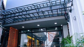 Um edifício moderno com um alpendre coberto, com uma mesa, cadeiras, escadas e plantas em vasos.