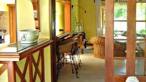 Um interior acolhedor com área de refeições, móveis de vime e vista através de uma porta de vidro.