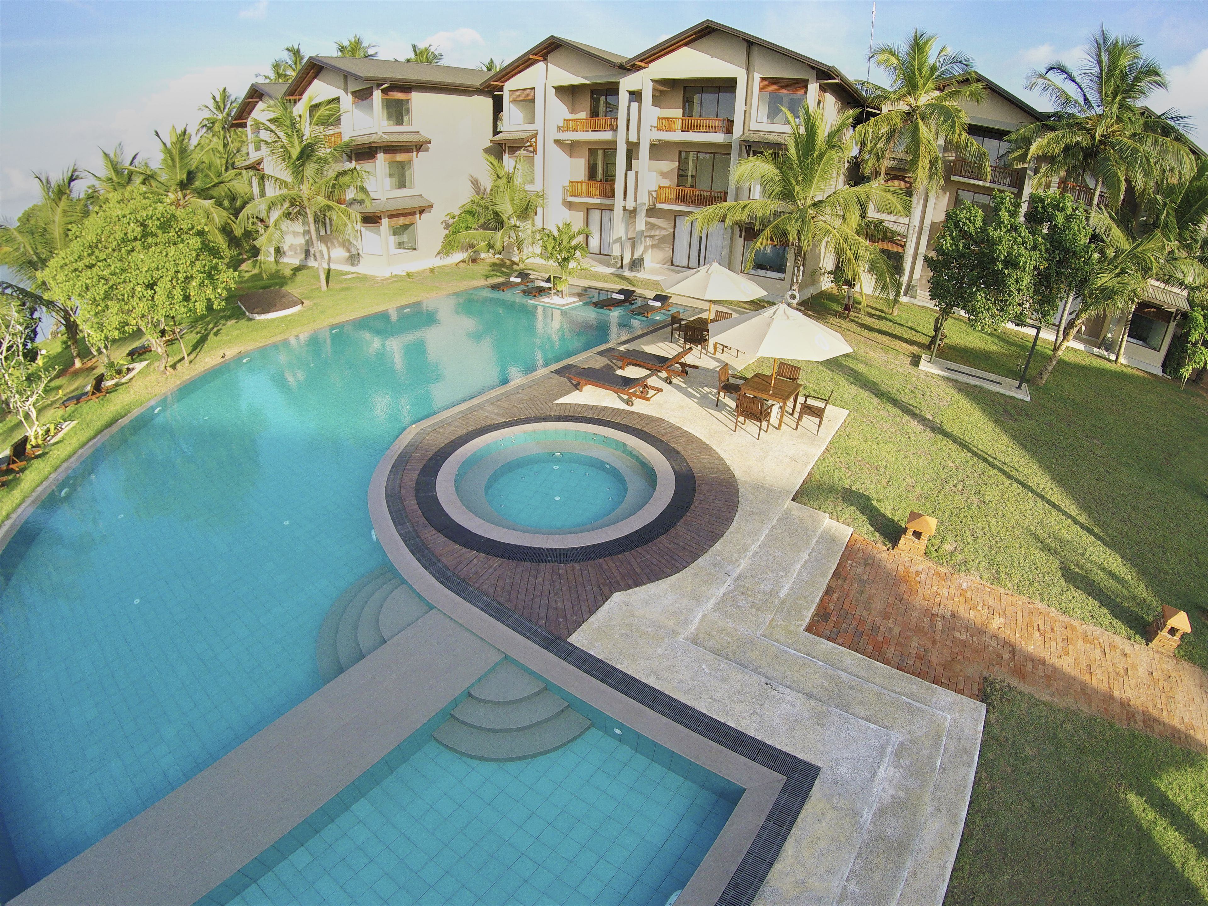 Um resort com uma grande piscina, várias varandas e palmeiras.