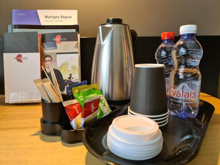 Bandeja de café da manhã com cafeteira, garrafas de água, caneca e lanches embalados.
