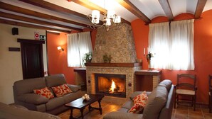 Uma sala de estar aconchegante com lareira de pedra, sofás e um candelabro.