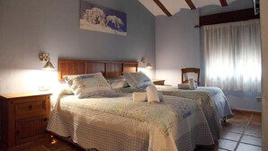 Quarto com duas camas, cabeceiras de madeira e uma pintura de nuvens na parede.