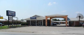 Um motel com um grande letreiro, uma lavanderia e um estacionamento.