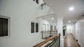 Interior com vários níveis, uma escada de madeira, paredes brancas e piso revestido de azulejos.