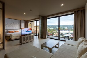 Quarto de hotel moderno com varanda, televisão de tela plana, sofá e mesa de jantar.
