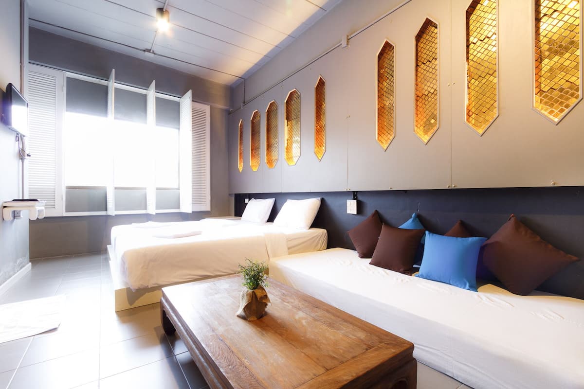 Quarto de hotel com duas camas, uma mesa de centro de madeira e painéis decorativos na parede.