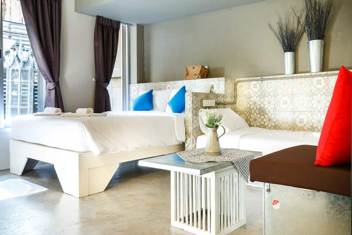 Quarto de hotel com duas camas, uma mesa pequena e um sofá.