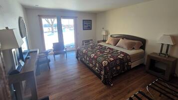 Quarto de hotel com cama, escrivaninha, cadeira e janela.