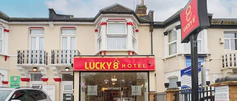 Um edifício com uma placa indicando 'Lucky 8 Hotel' e uma placa de 'Proibido Estacionar'.