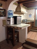 Cozinha com dispensador de água, geladeira, cafeteira, torradeira e pia.