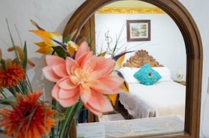 Quarto com cama, espelho e um arranjo floral.
