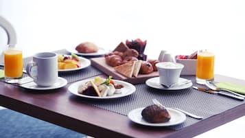 Uma mesa de café da manhã com pratos de comida, um croissant, um muffin e dois copos de suco de laranja.