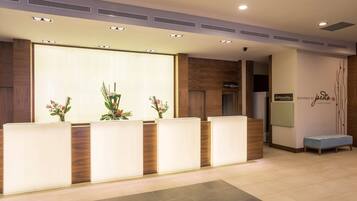 Uma área de recepção com design moderno, com balcão de atendimento, um banco e plantas decorativas.