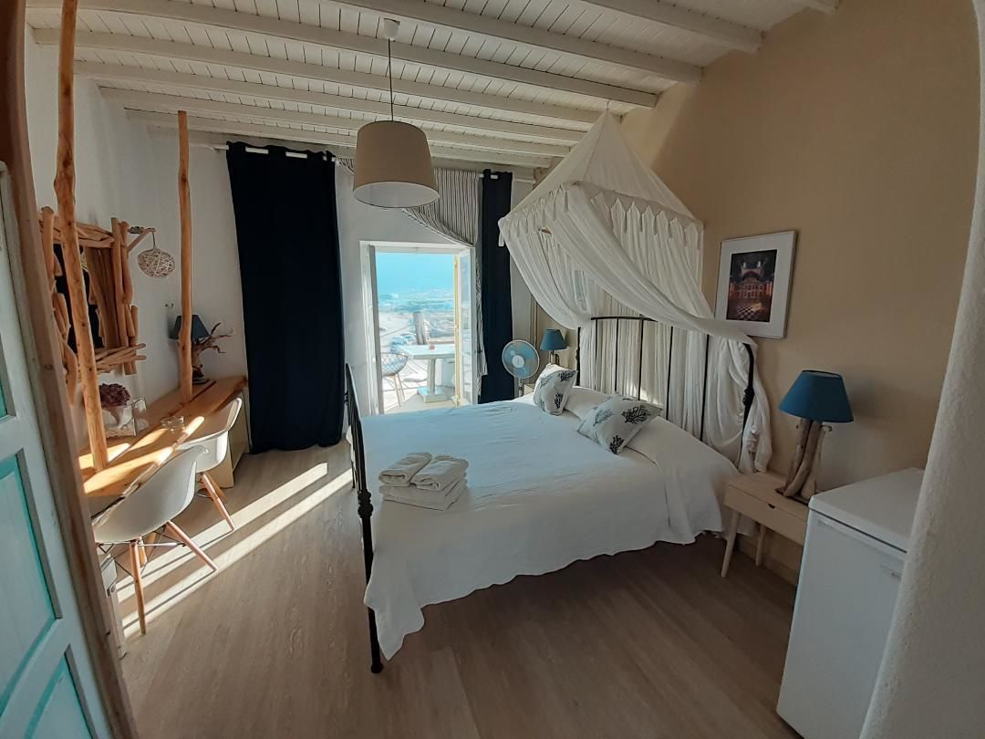 Quarto com cama, luminárias de cabeceira, escrivaninha e cadeira.