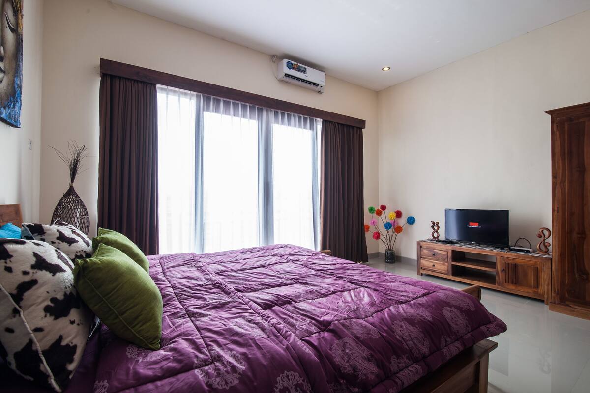 Quarto com cama grande, televisão e armário de madeira.