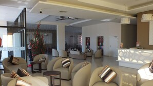 Um lobby moderno com sofás e poltronas, um balcão de recepção e um pinheiro de Natal.