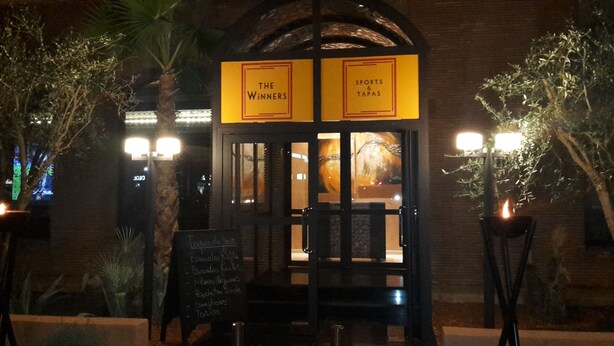 Entrada de restaurante com uma placa que diz 'The Winners' e 'Sports & tapas'.