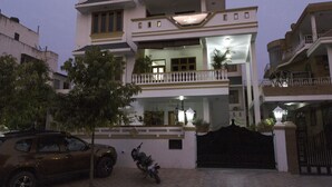 Um edifício com vários andares, uma varanda, um carro e uma motocicleta estacionados na frente.
