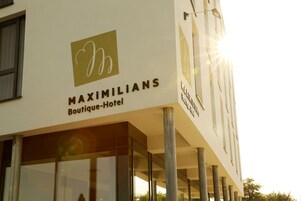 Exterior do Maximilians Boutique-Hotel, com vista clara da fachada e da sinalização.