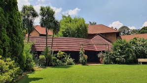 Um edifício com telhado de telhas vermelhas, cercado por vegetação exuberante e um gramado bem cuidado.