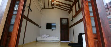 Um quarto japonês tradicional, com piso de tatame, porta deslizante e televisão na parede.