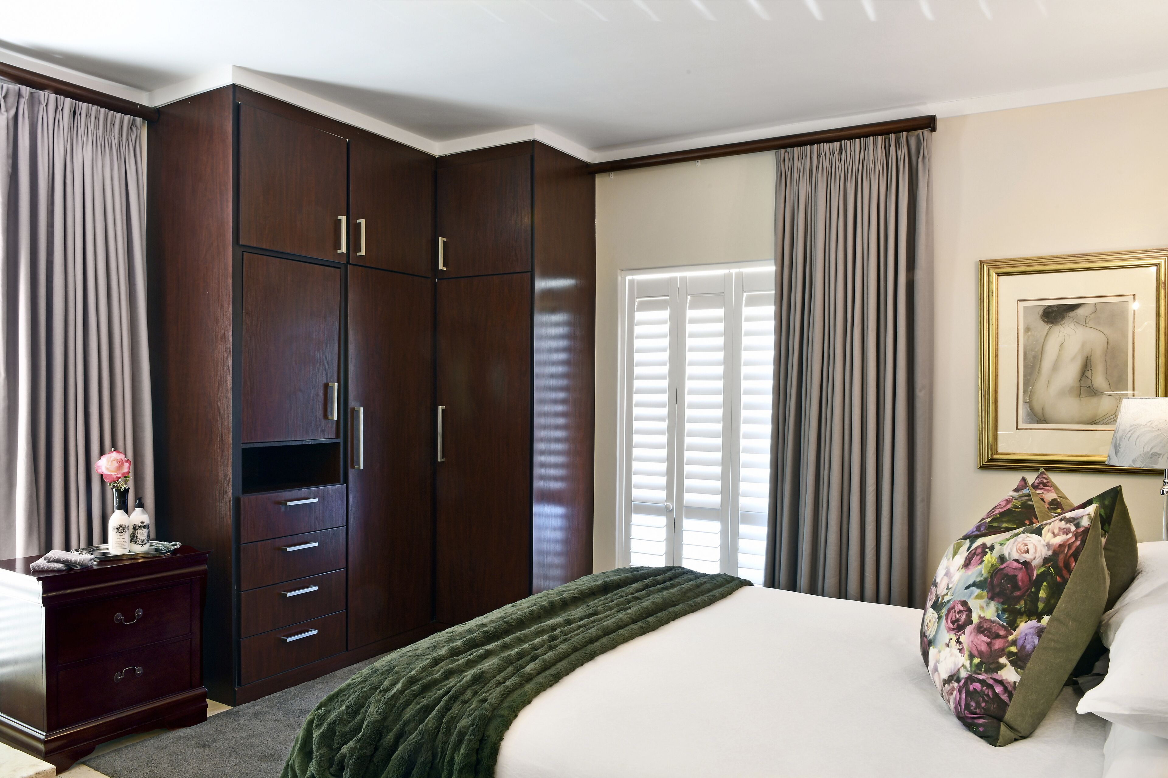 Quarto com cama, guarda-roupa, mesa de cabeceira e janela com cortinas.