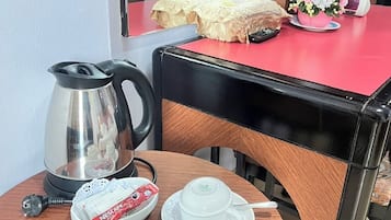 Quarto de hotel com uma mesa de madeira posta para chá, chaleira e um objeto decorativo pequeno.