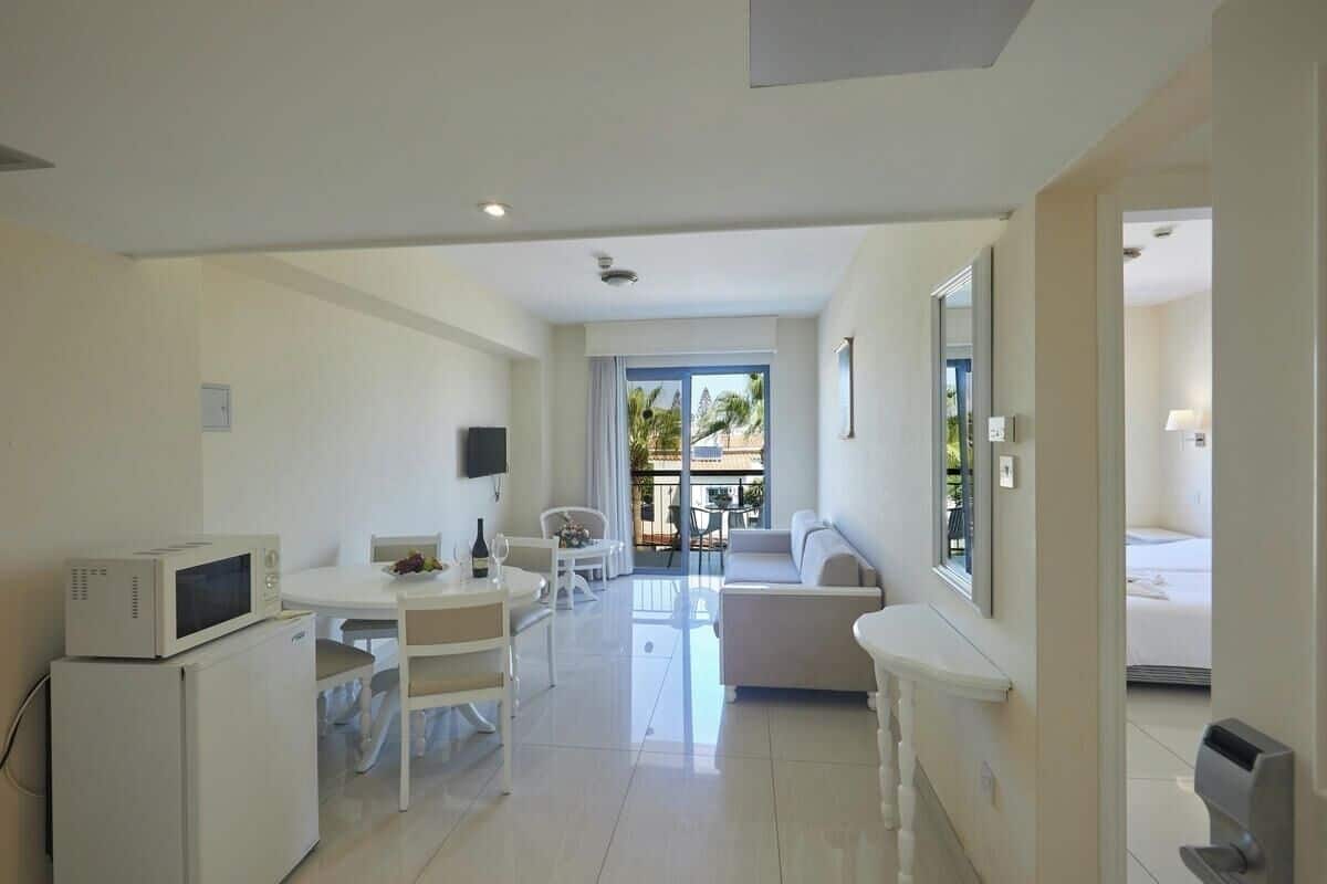 Quarto moderno e bem iluminado com área de refeições, sofá e cama.
