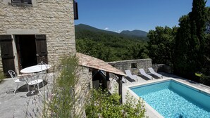Um edifício de pedra com piscina, área de estar externa e vista para montanhas.