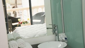 Um banheiro de hotel com um espelho grande, um lavatório redondo e toalhas dobradas com capricho.
