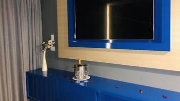 Um quarto com uma mesa consola azul, uma televisão de ecrã plano na parede e uma cortina.
