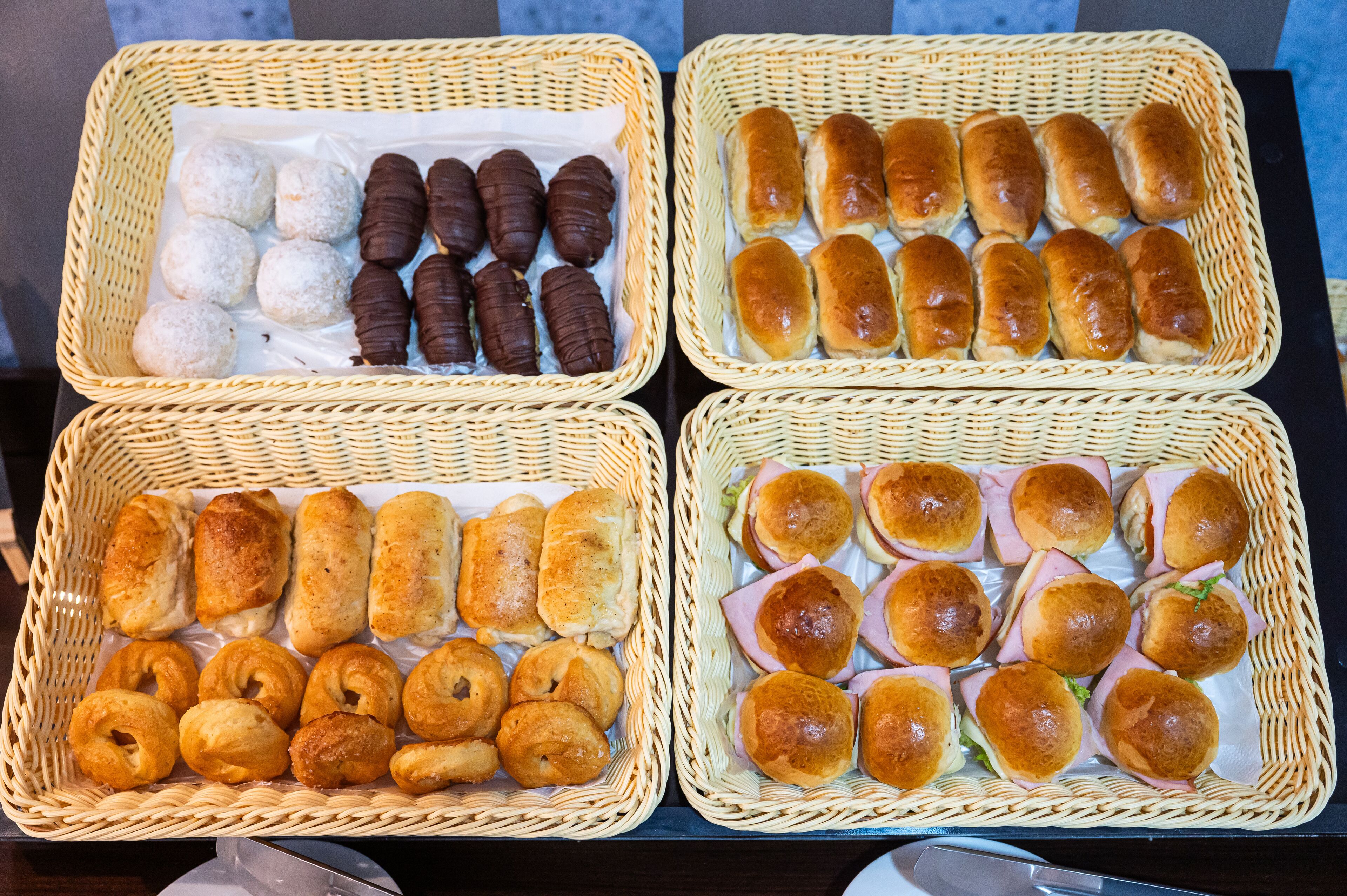 Quatro cestos de vime com diversos produtos de pastelaria.