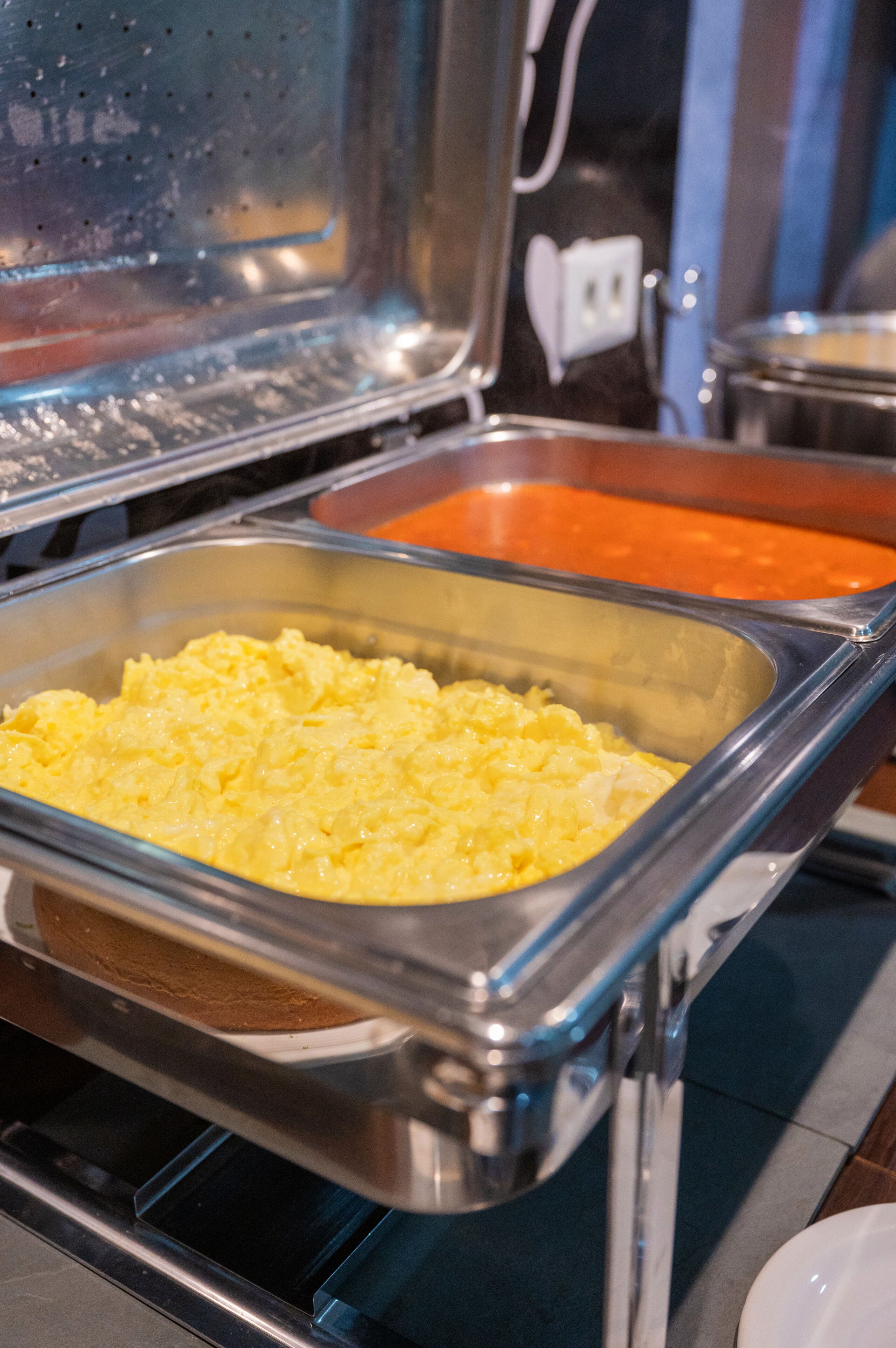 Buffet com ovos mexidos e molho vermelho.