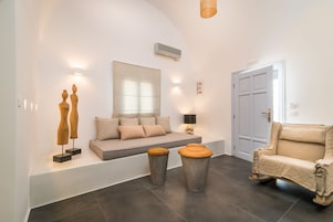 Uma sala de estar moderna com um sofá, dois banquinhos, uma cadeira e esculturas de madeira decorativas.