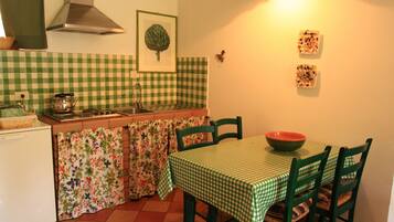 Uma cozinha com painel de fundo xadrez, fogão e mesa com cadeiras.