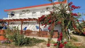 Um edifício com fachada branca, várias varandas e uma pérgula de madeira.