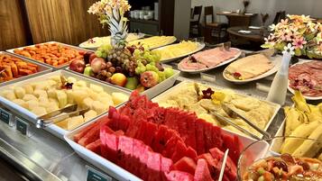 Um buffet com diversas frutas e legumes, incluindo melancia, abacaxi e uvas.