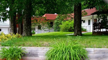 Uma área residencial com gramado bem cuidado, um deck de madeira e uma casa com telhado vermelho.