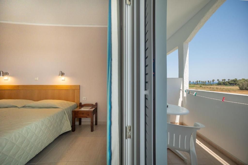 Quarto com cama, mesa de cabeceira e vista para o exterior.