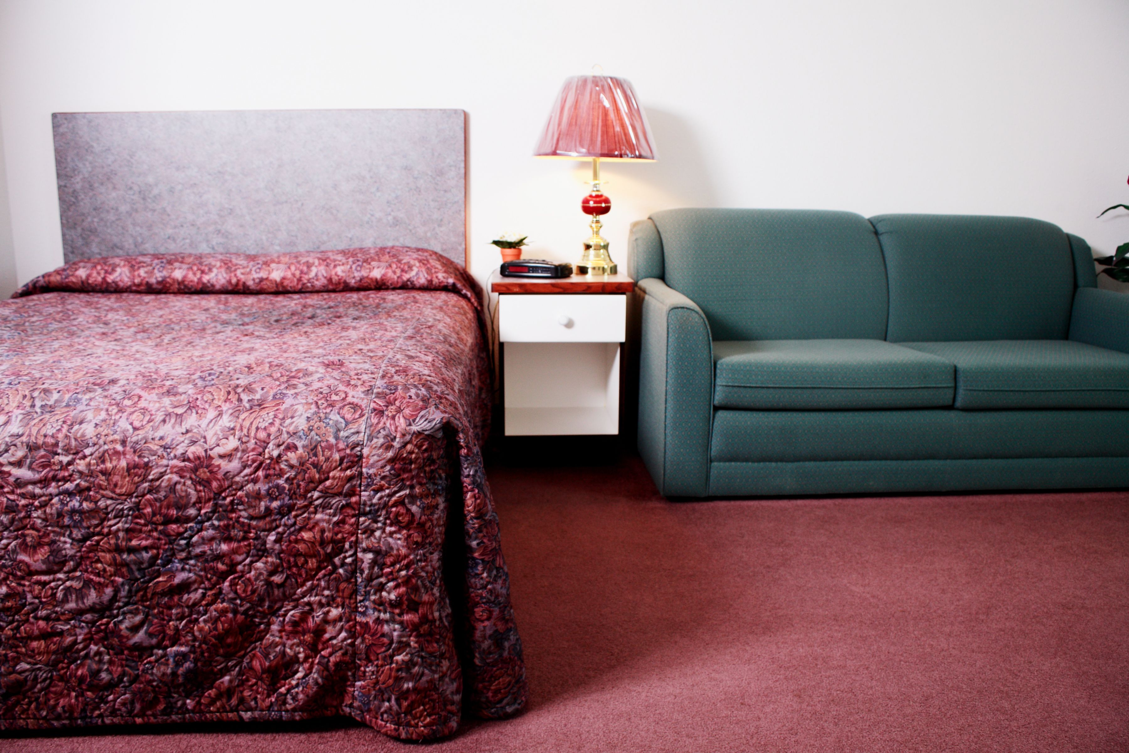 Quarto com cama, mesa de cabeceira, luminária e sofá.